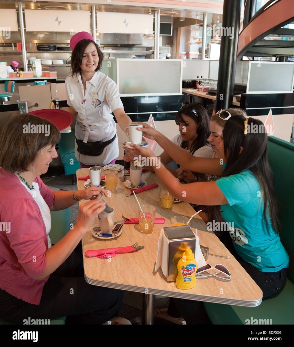 A teenage waitress serving food to a family, Annettes Diner, Disneyland ...