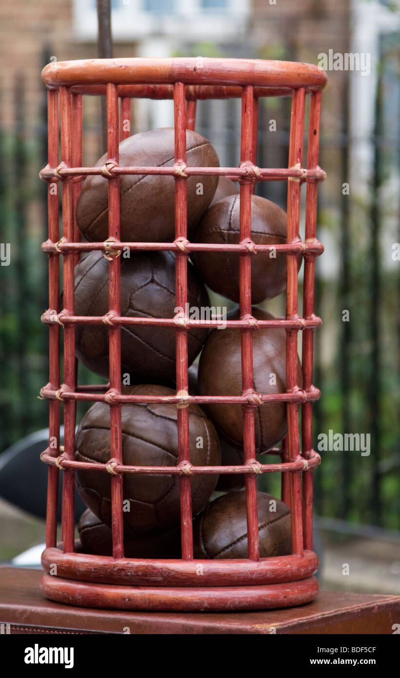 Small size old fashioned leather rugby balls and footballs in a caged ...