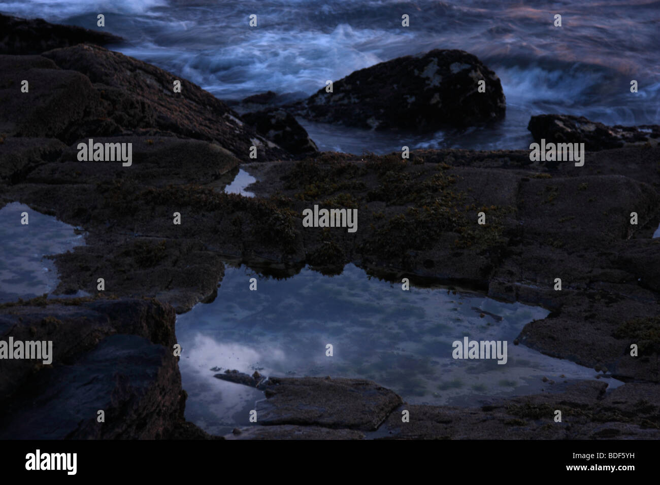 Clouds reflected in rock pool at sunset, using a long shutter time ...