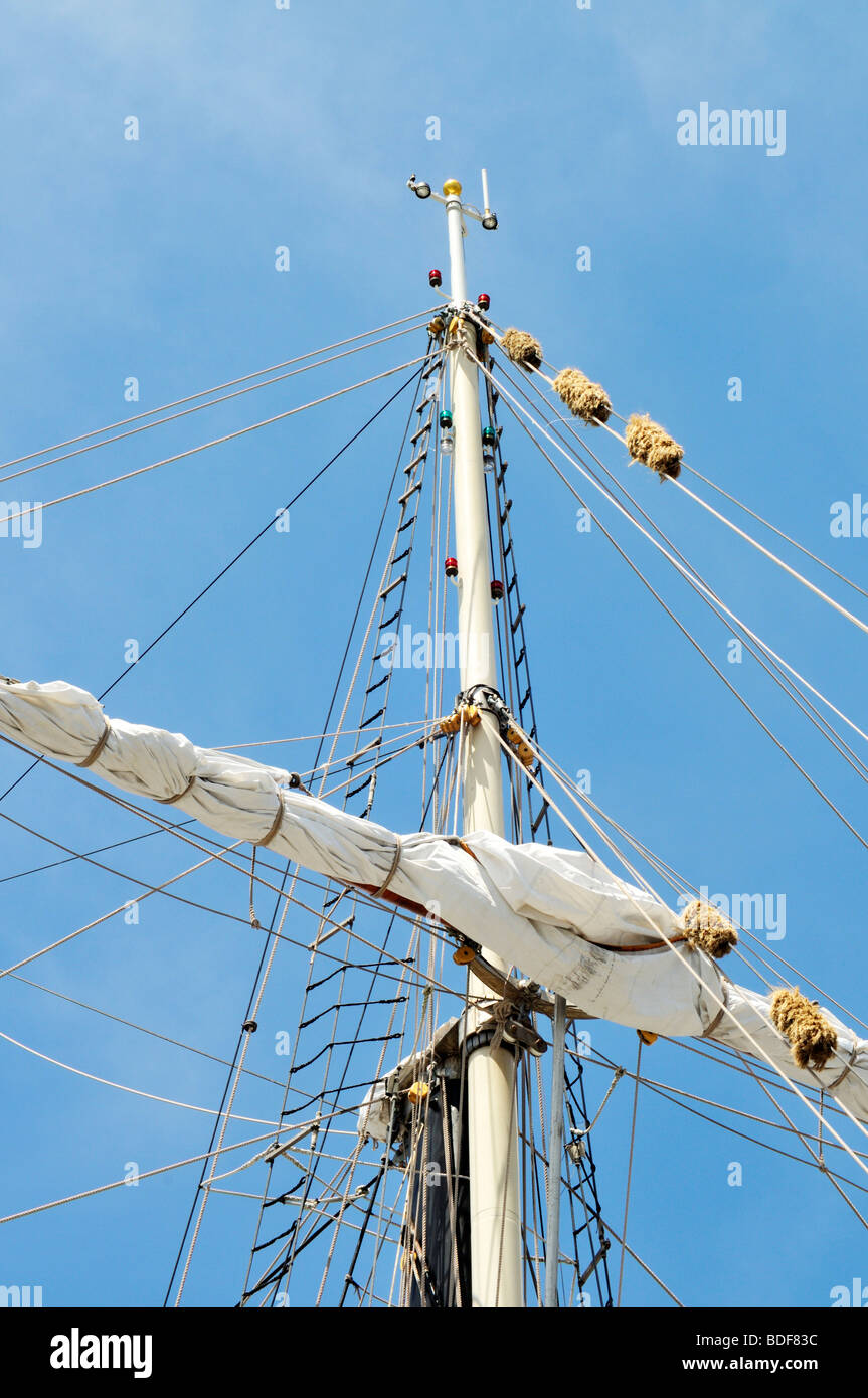 Upper mast with sail furled on yardarm, shrouds, rigging, lines and ...