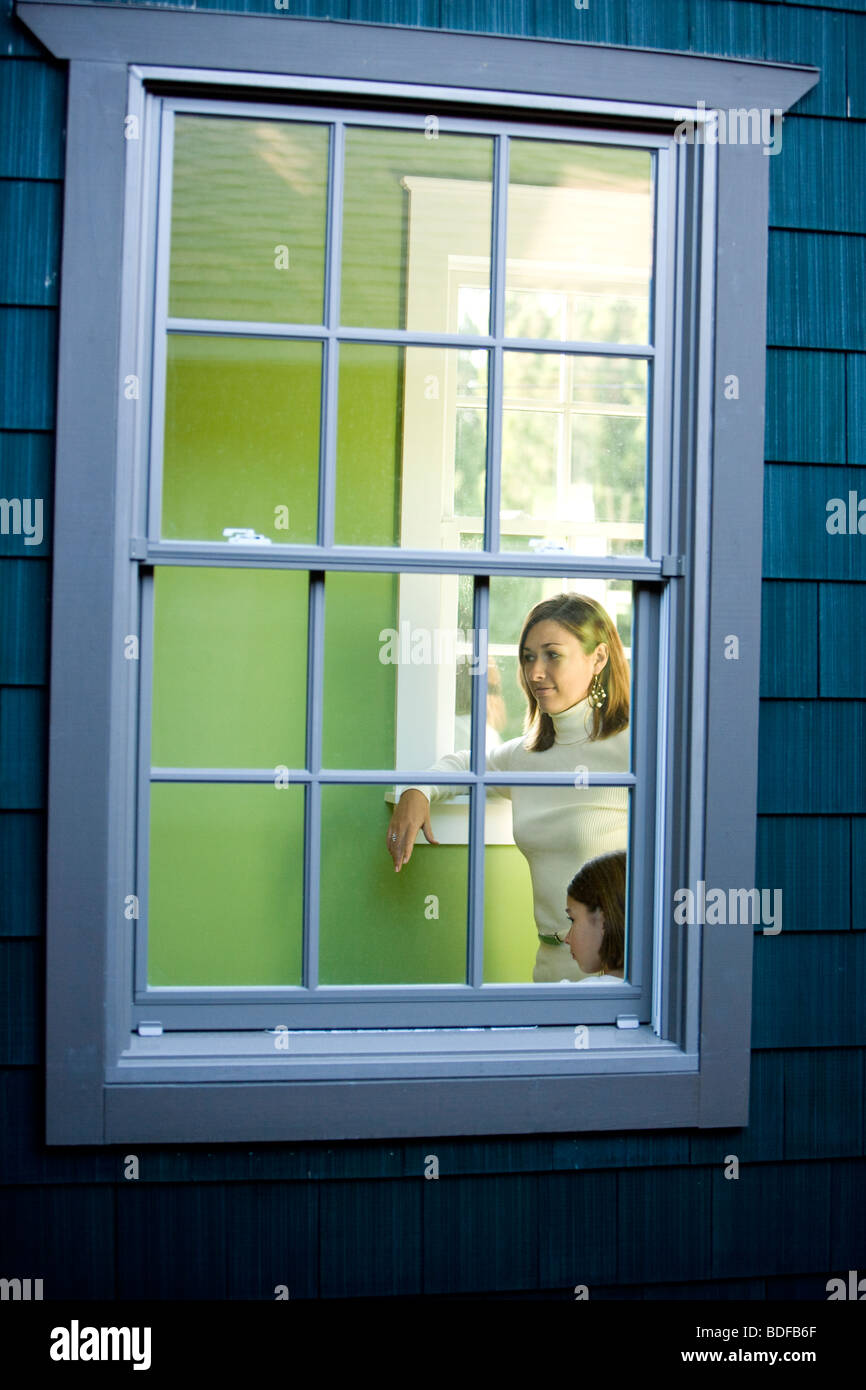 Window view of mother and daughter standing inside Stock Photo - Alamy