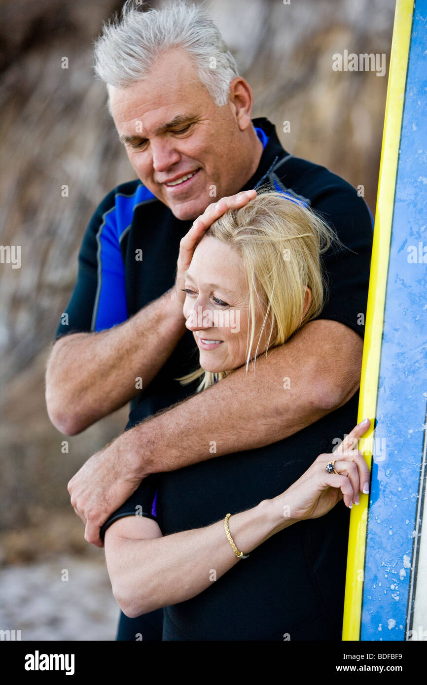 Middle-aged surfer couple on beach with surfboard Stock Photo - Alamy