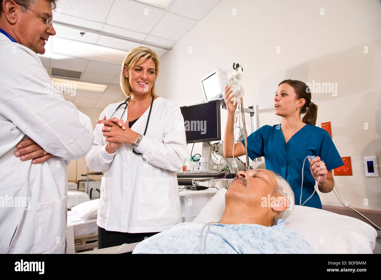 Doctors and nurse in hospital recovery room with patient Stock Photo ...