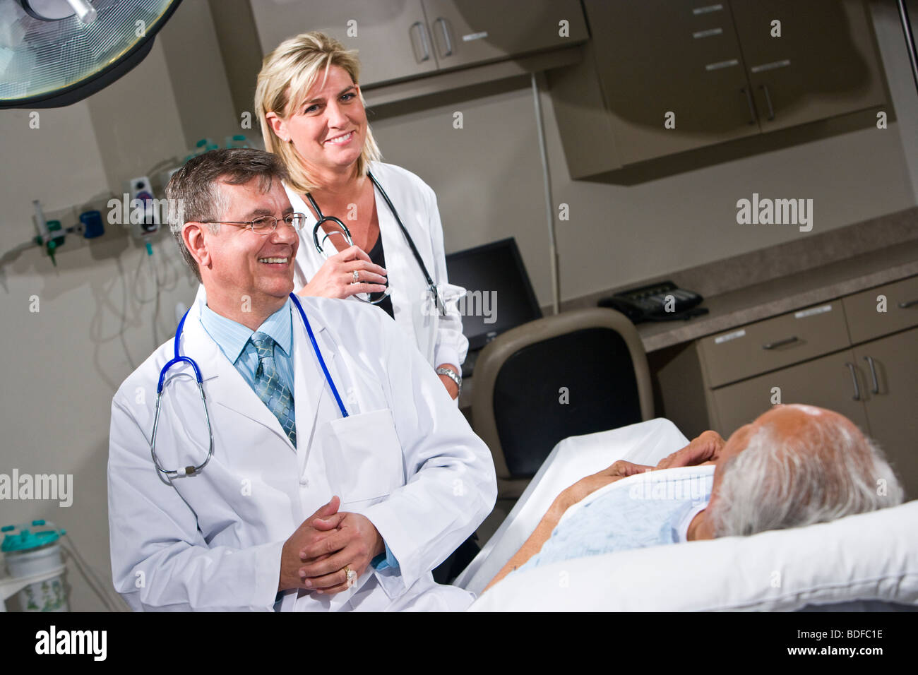 Doctors with patient in hospital room Stock Photo - Alamy