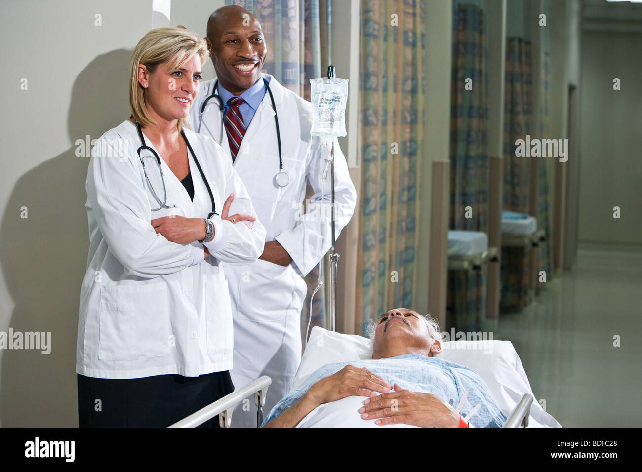 Multi-ethnic doctors standing with patient in hospital Stock Photo - Alamy