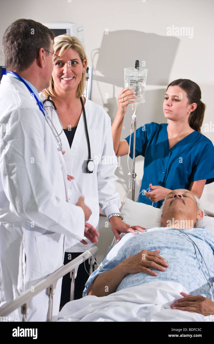 Doctors and nurse in hospital room with patient Stock Photo - Alamy