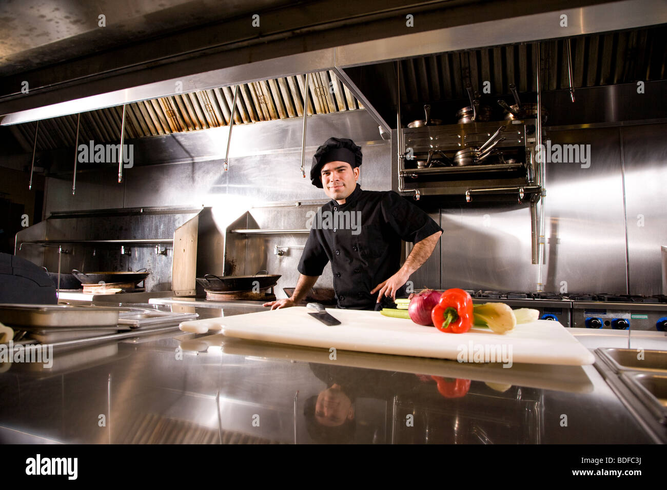 Professional chef in restaurant kitchen with cutting board and ...
