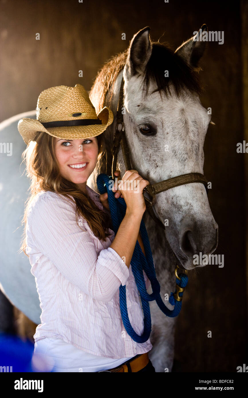 Young woman with white Gelding horse in stable Stock Photo - Alamy