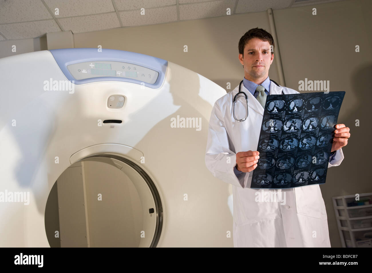 Radiologist holding test results next to CT scanner Stock Photo - Alamy