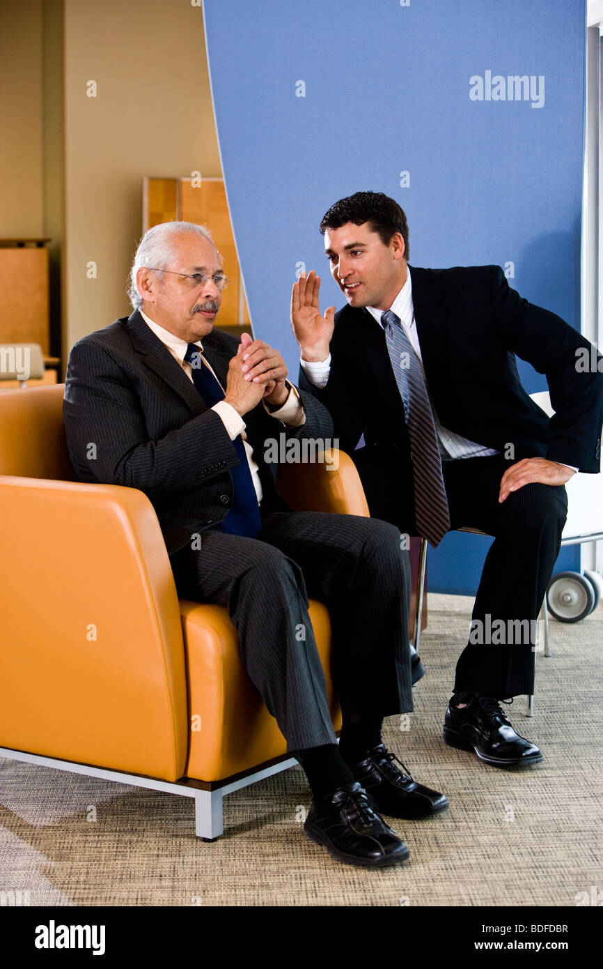 Portrait of two Hispanic businessmen talking in office lounge area ...