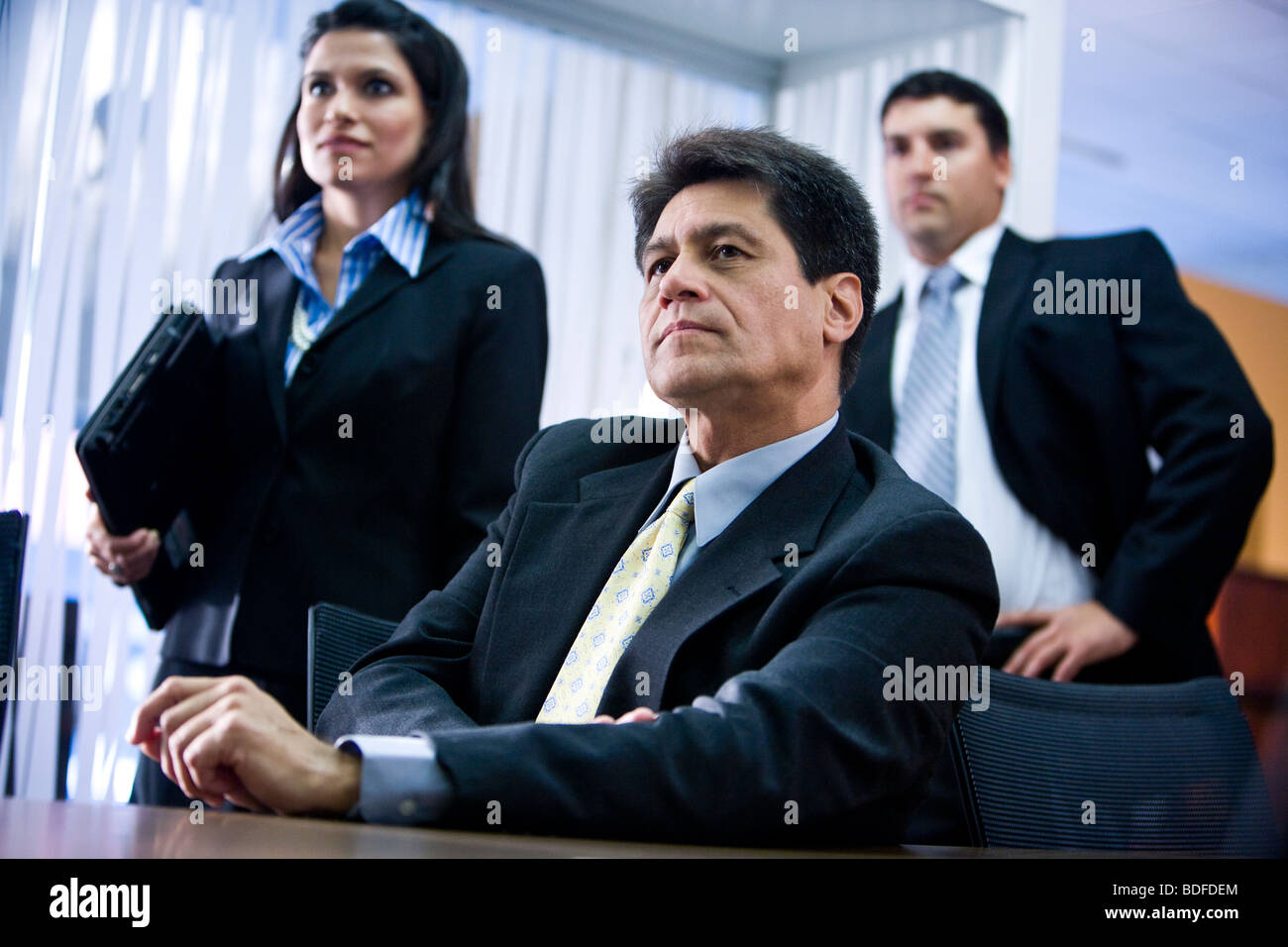 Hispanic businessman in meeting with younger colleagues behind Stock ...