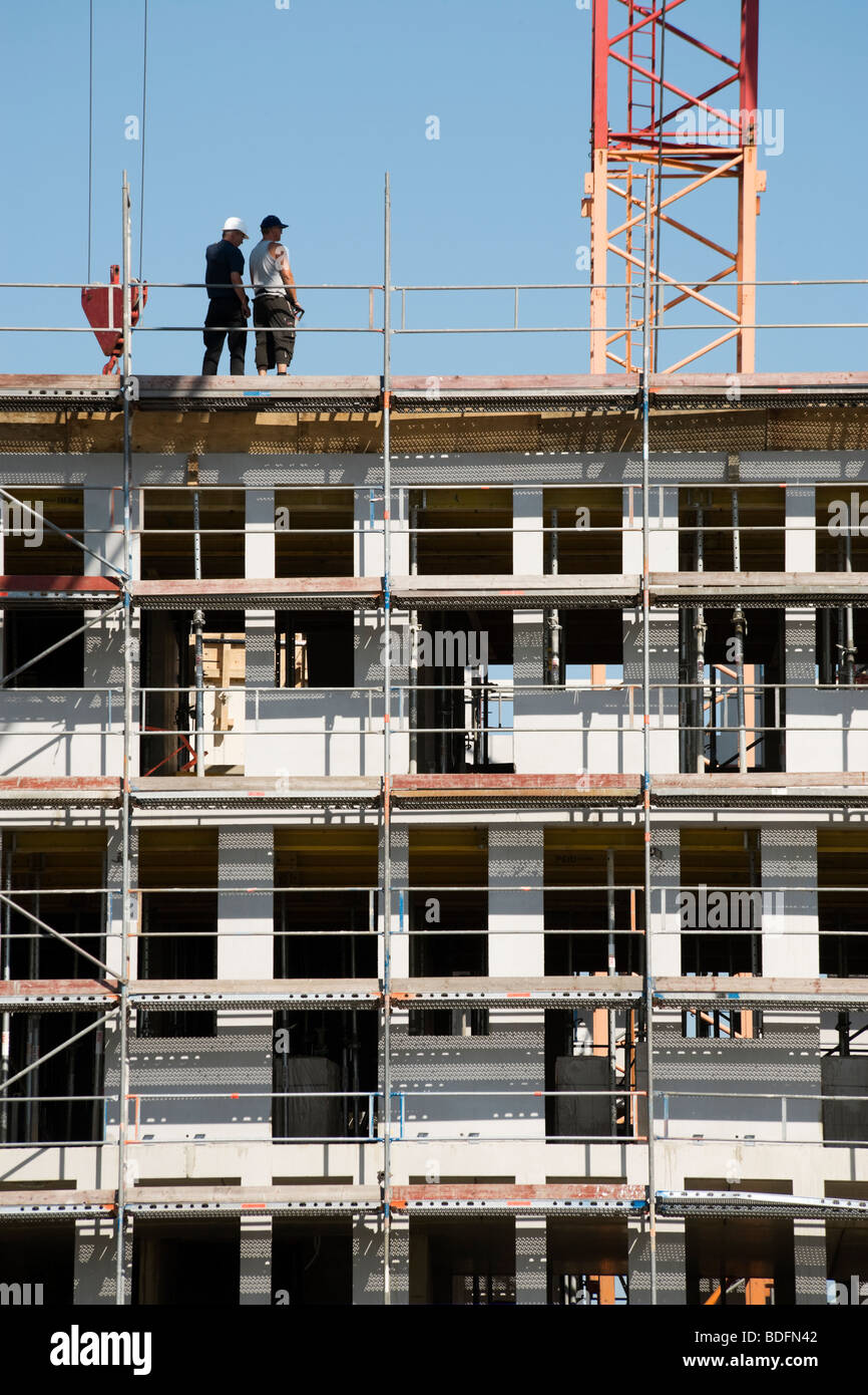 two construction workers on top of office building under construction ...