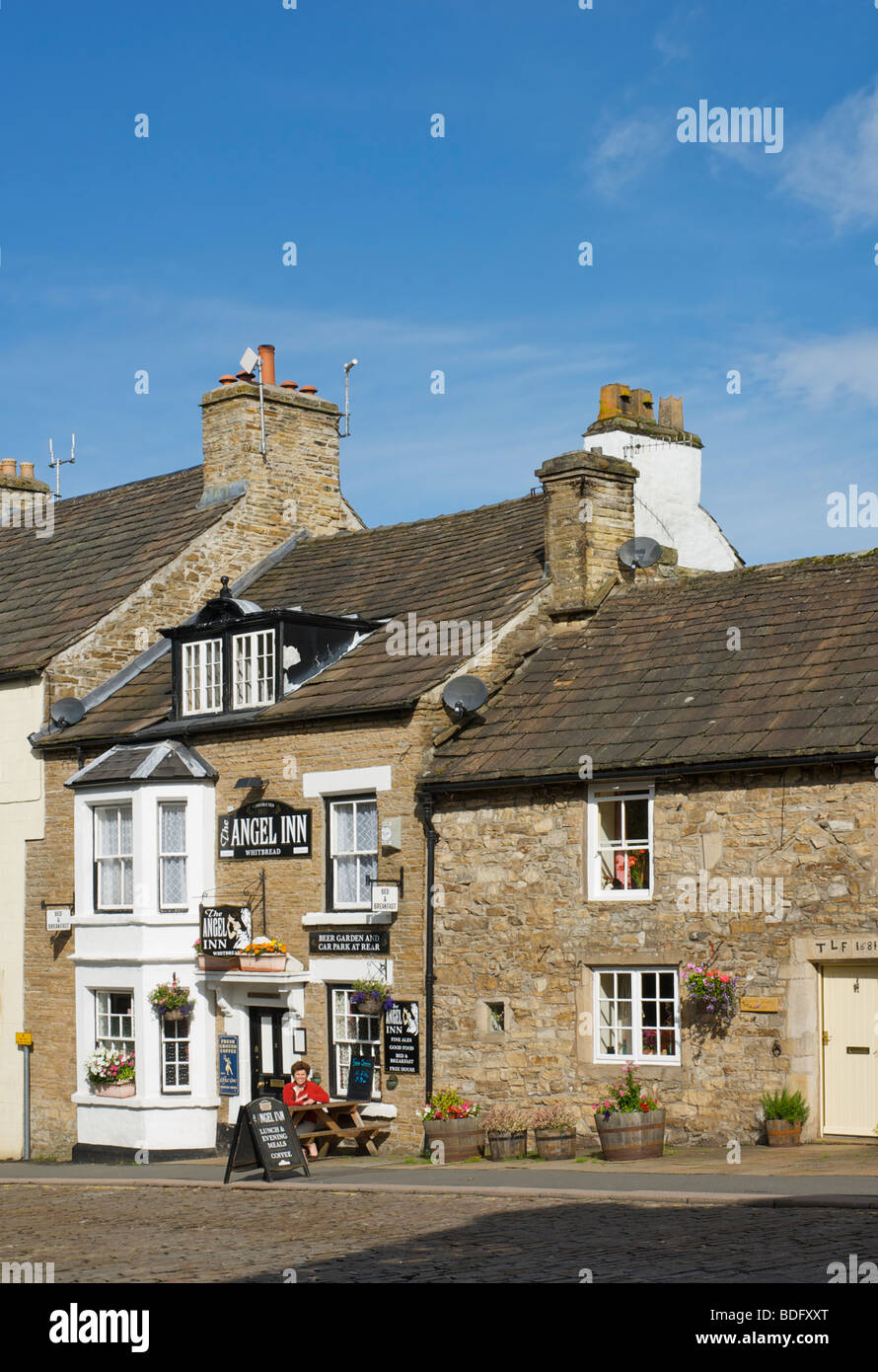 Woman sitting outside the Angel Inn, in Alston, Cumbria, England UK ...