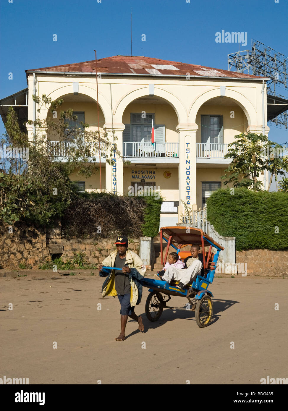 A rickshaw driver passes by a colonial building in Ambositra ...