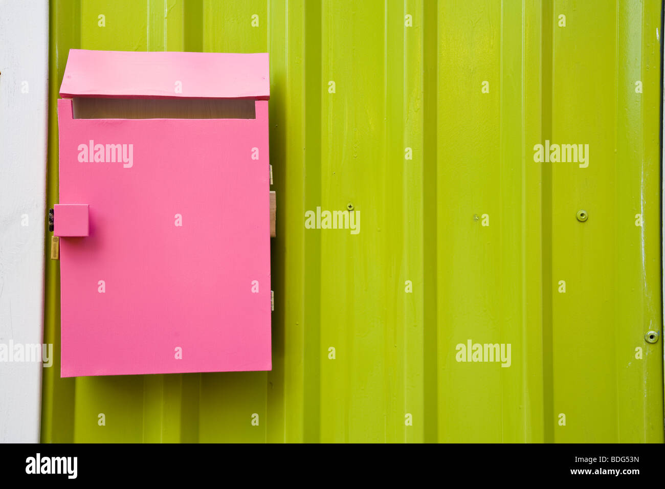 Bright pink letter box against a green wall Stock Photo - Alamy