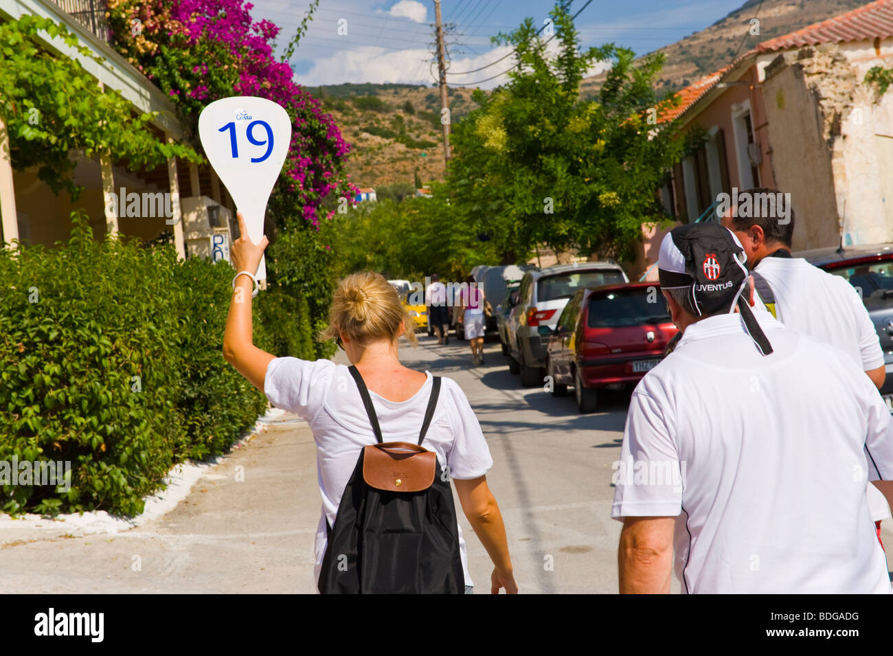 Organised tour group with guide 19 walking through village of Assos on ...