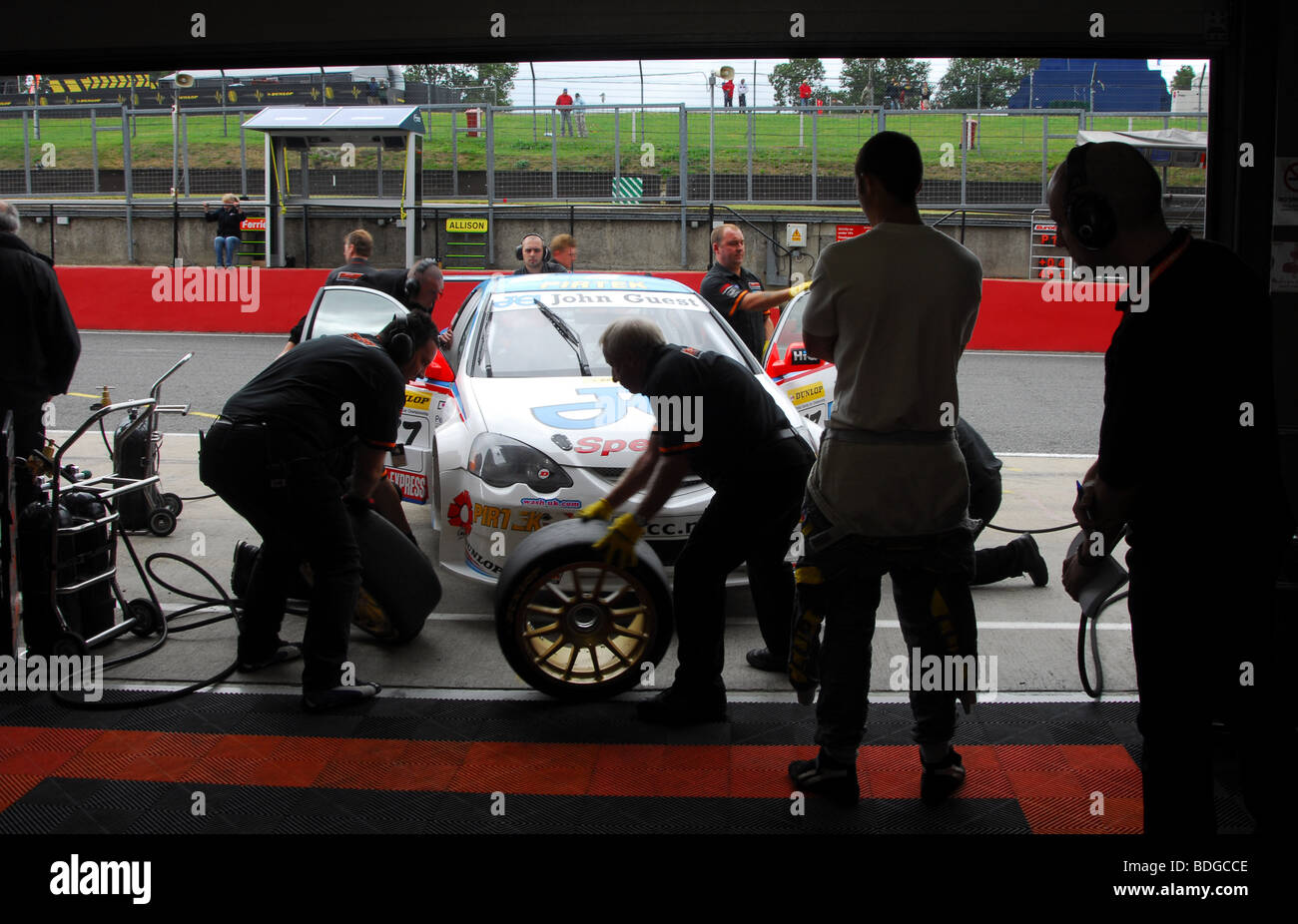 BTCC race mechanics prepare a racing car during a pit stop wheel change ...
