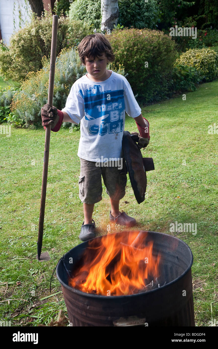 Young boy aged seven burning rubbish in garden Stock Photo - Alamy