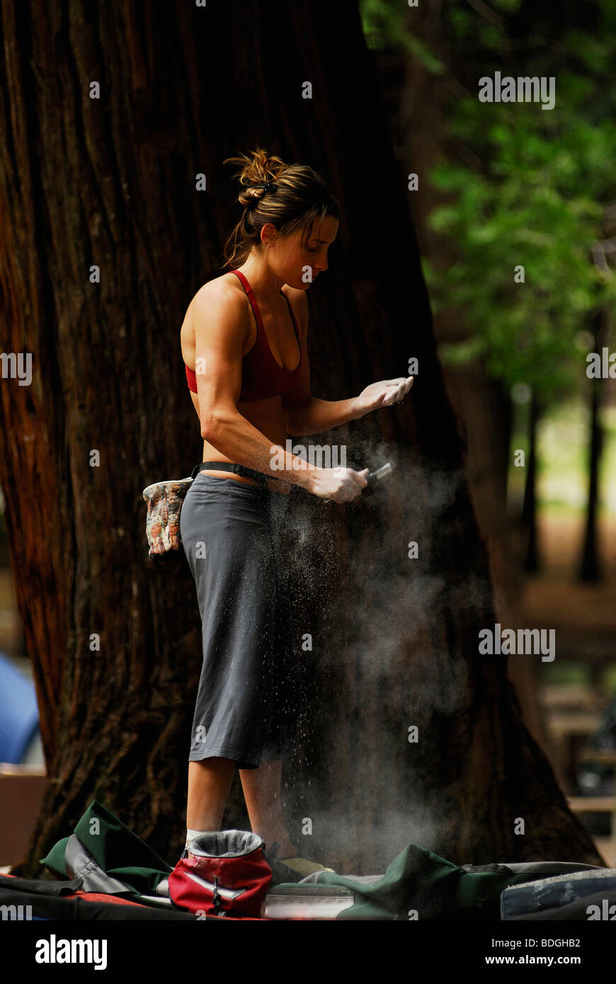 A woman putting chalk on her hands before rock climbing in Yosemite ...