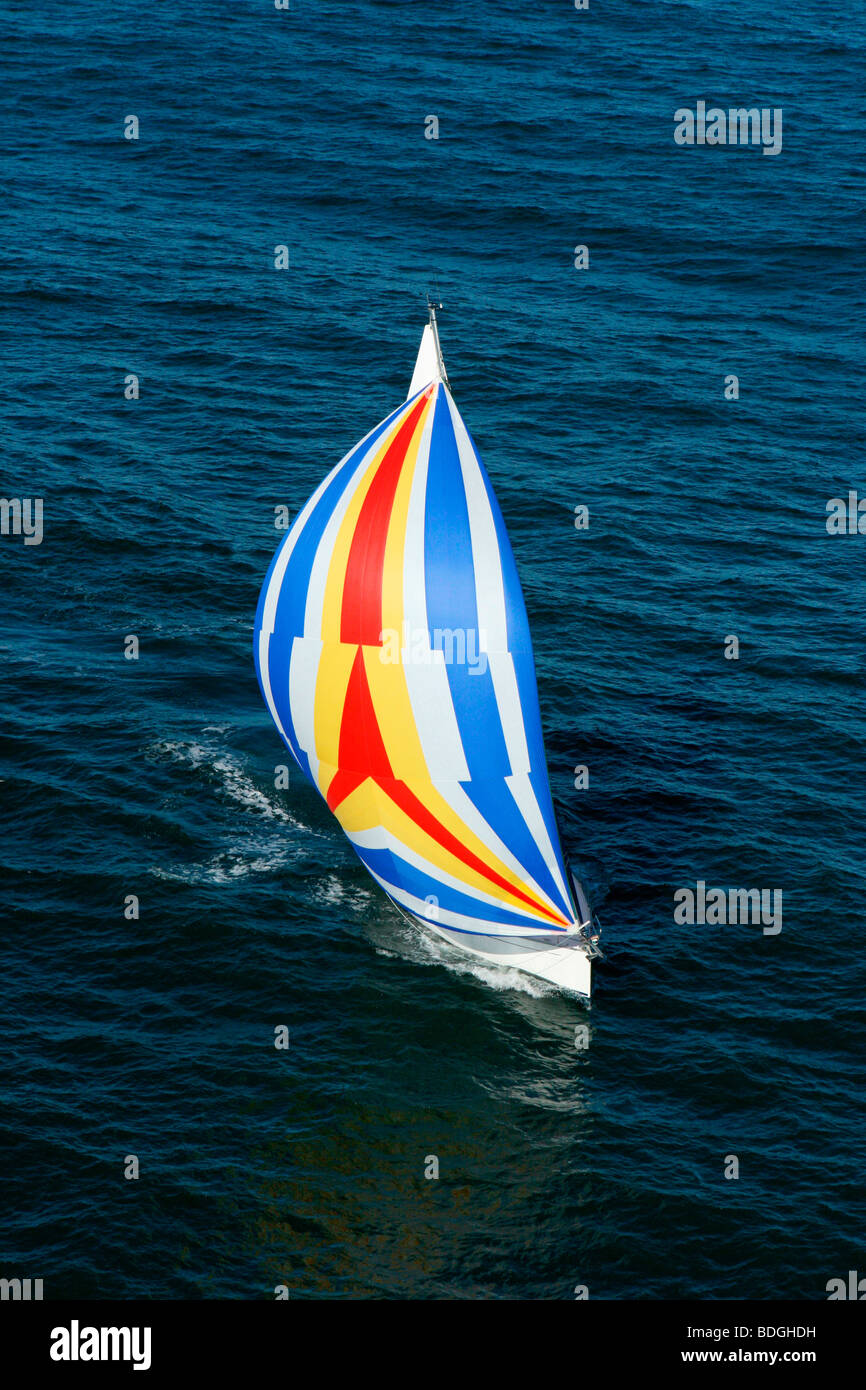 Aerial view of a sailing yacht with a colorful spinnaker cruising in ...