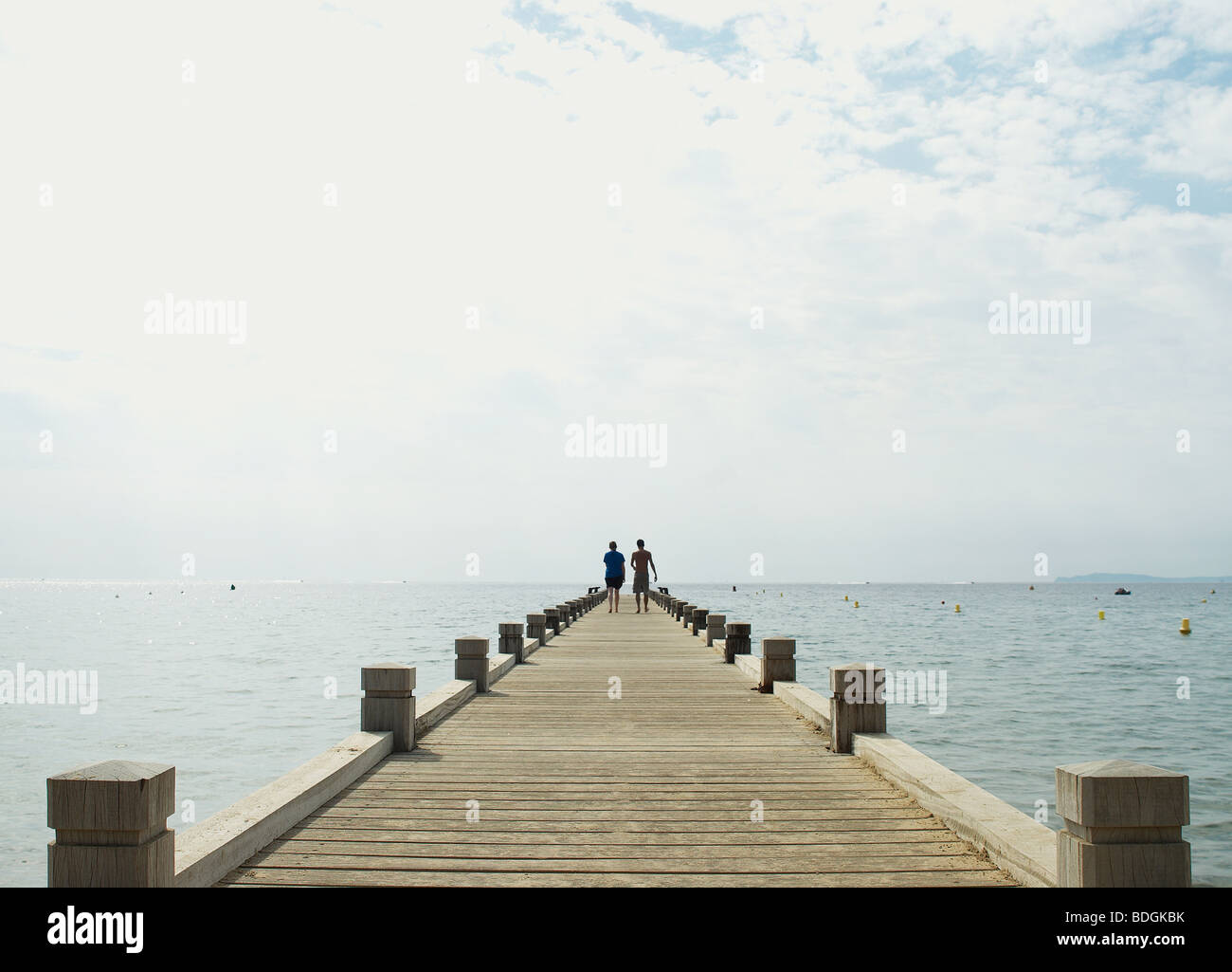 couple walking on small wooden pier looking out to sea Stock Photo - Alamy