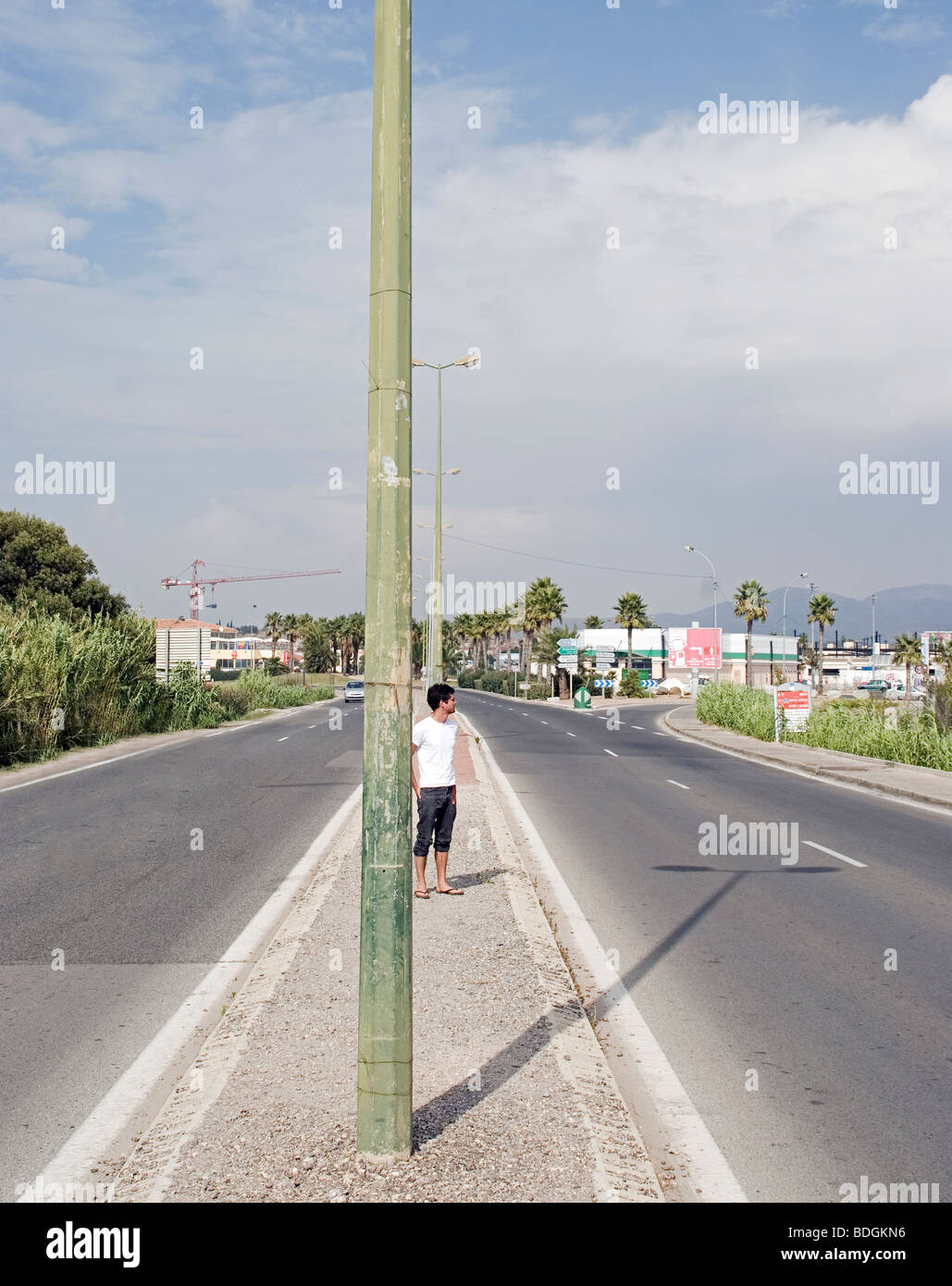 young man waiting to cross a dual carriageway Stock Photo - Alamy