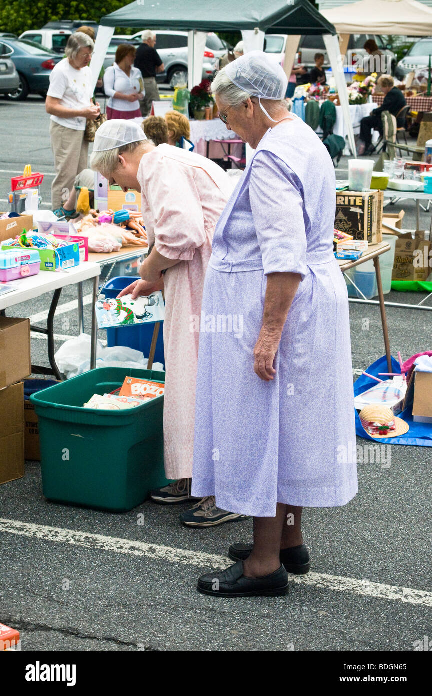 Two senior citizen, elderly women look over flea market sales items ...