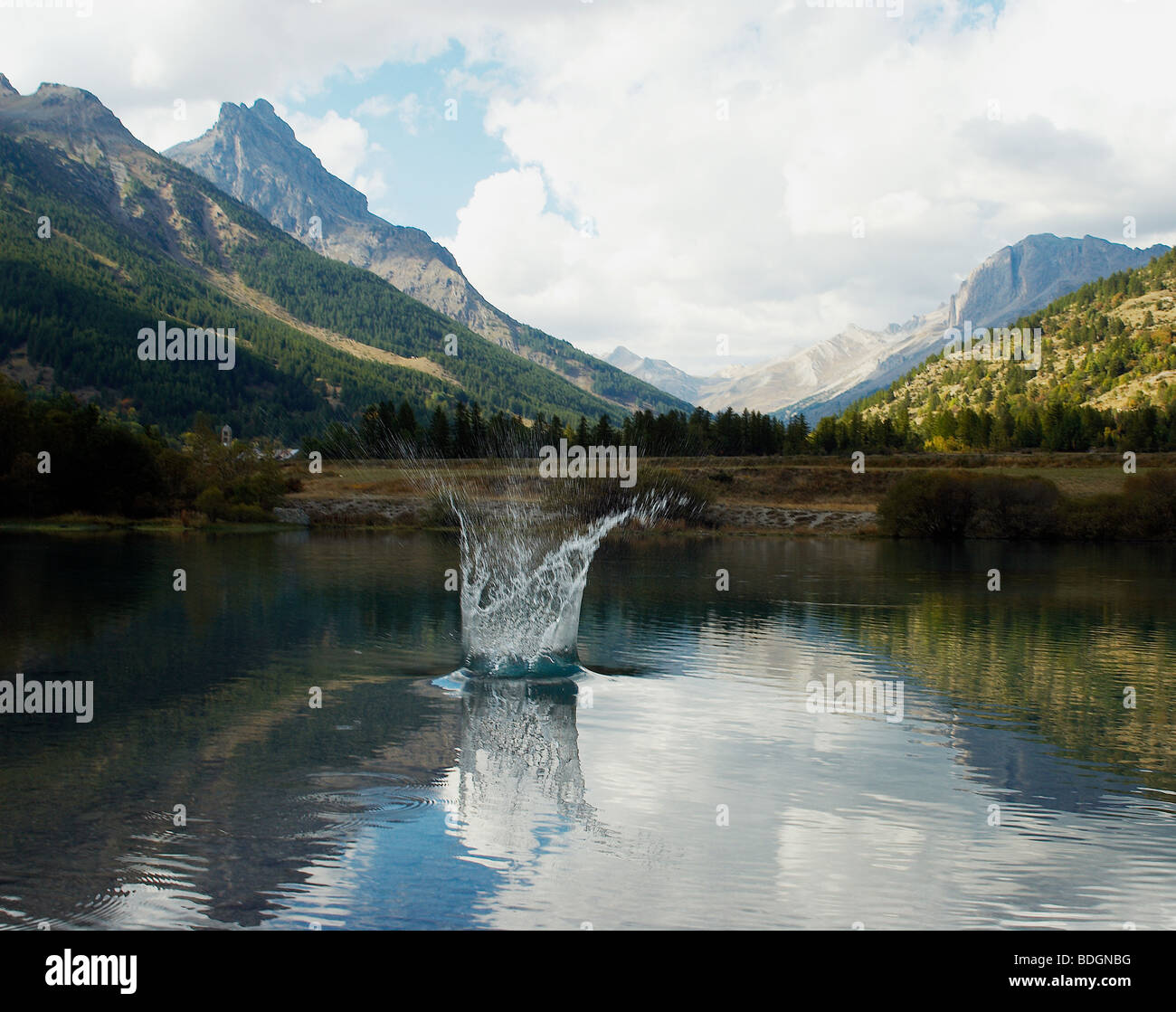 a view of the alps with a lake in the foreground. a splash of water ...