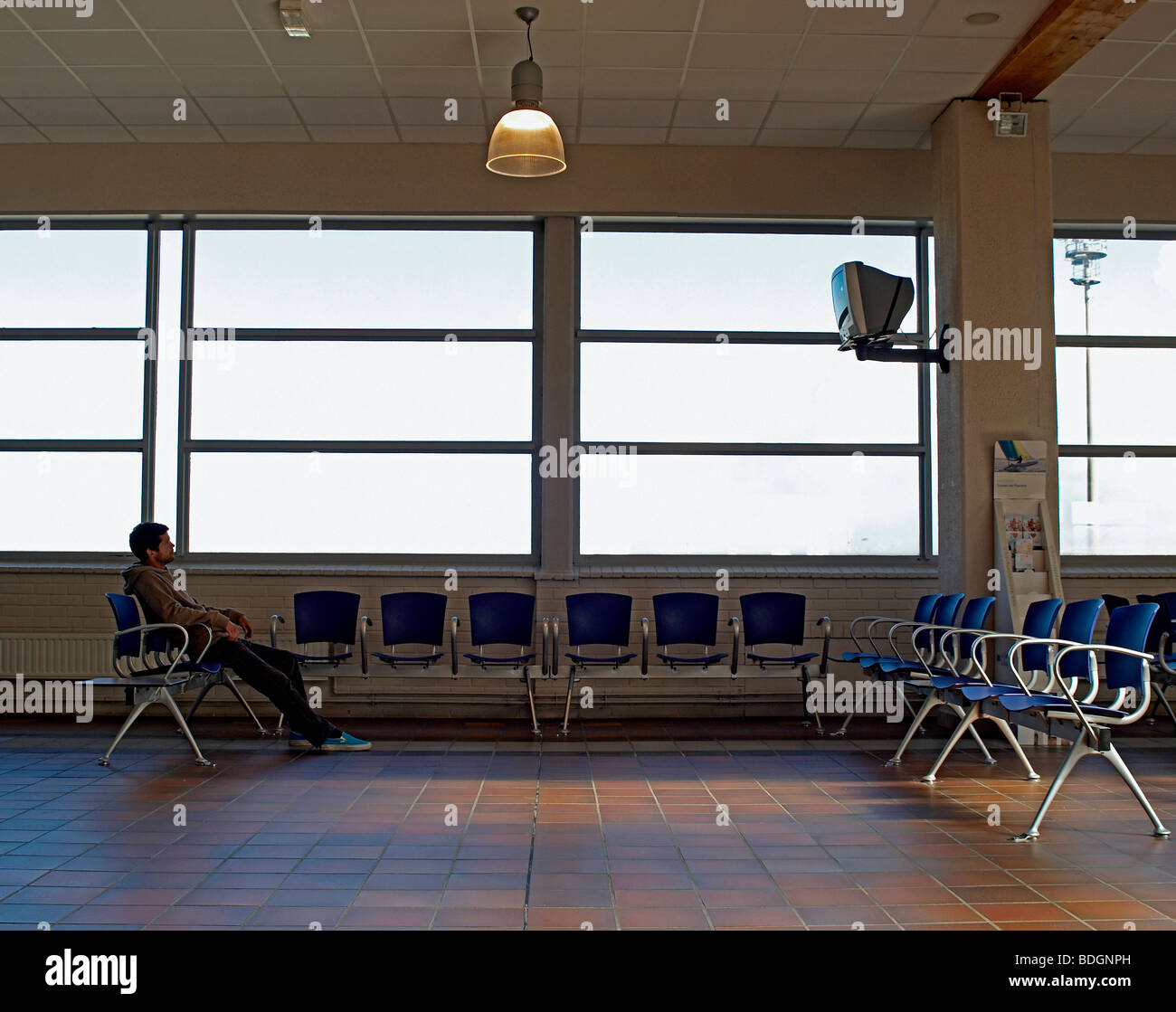Man sitting alone in empty waiting room watching a blank tv Stock Photo ...