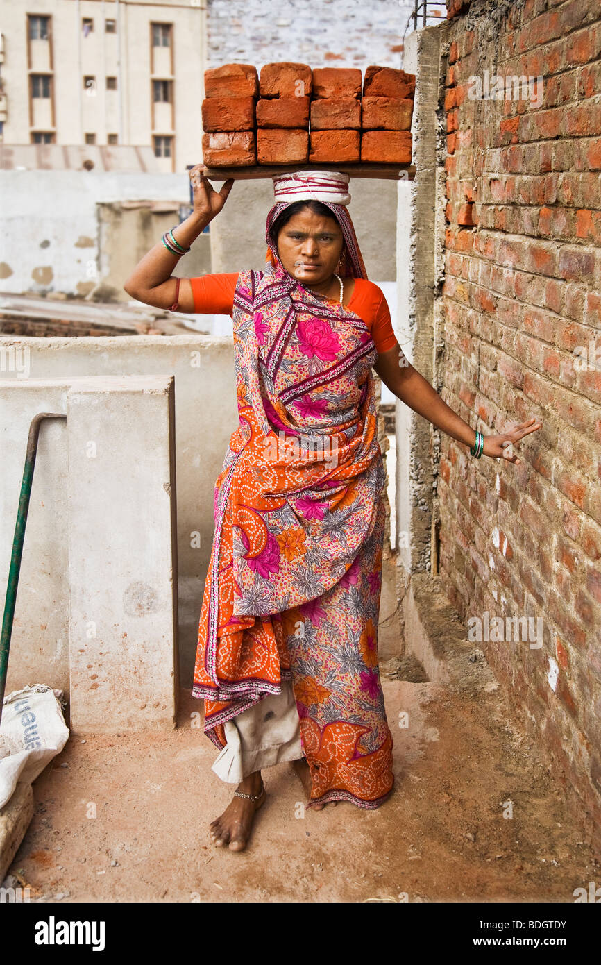 Women carrying bricks on her head. She is working on a construction ...