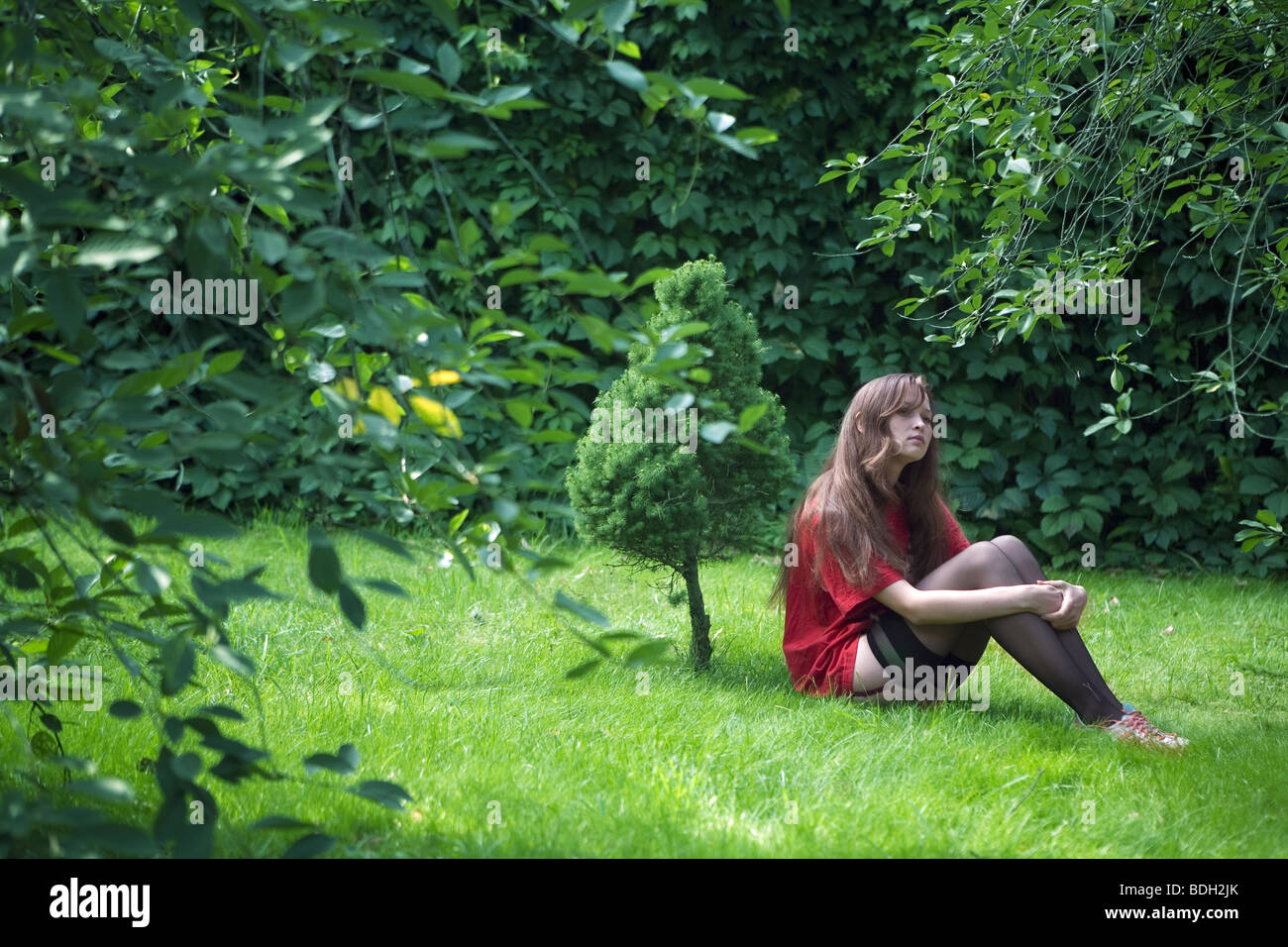 Young woman in red t-shirt and stockings sitting on grass Stock Photo ...