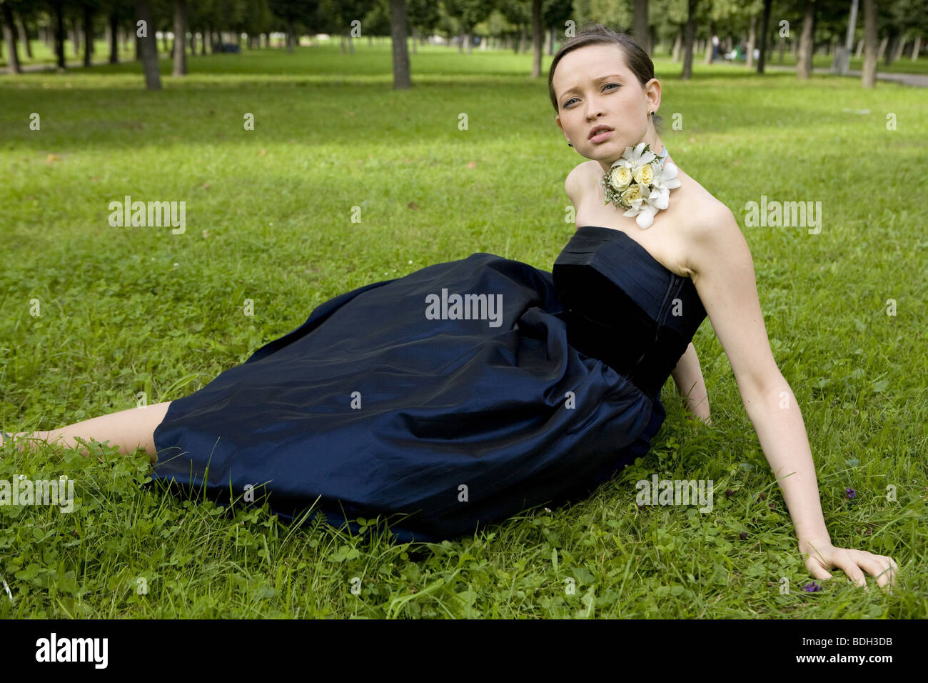 maid of honour with bouquet on neck sitting on grass Stock Photo - Alamy