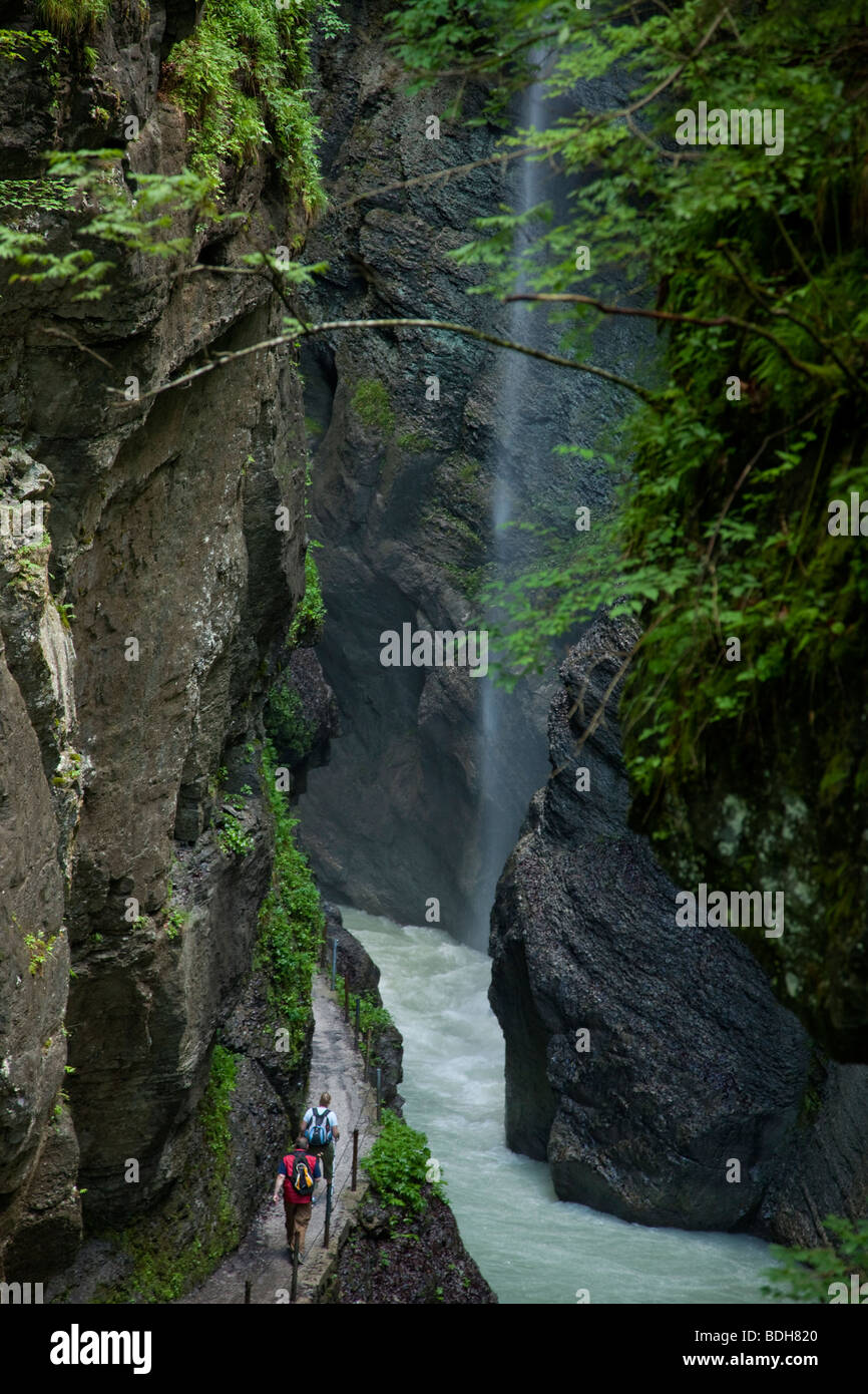 2 Hikers in the Partnachklamm gorge approaching a tall waterfall in ...
