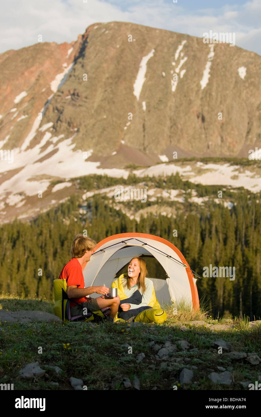 A young couple laughing in tent below a peak, San Juan National Forest ...