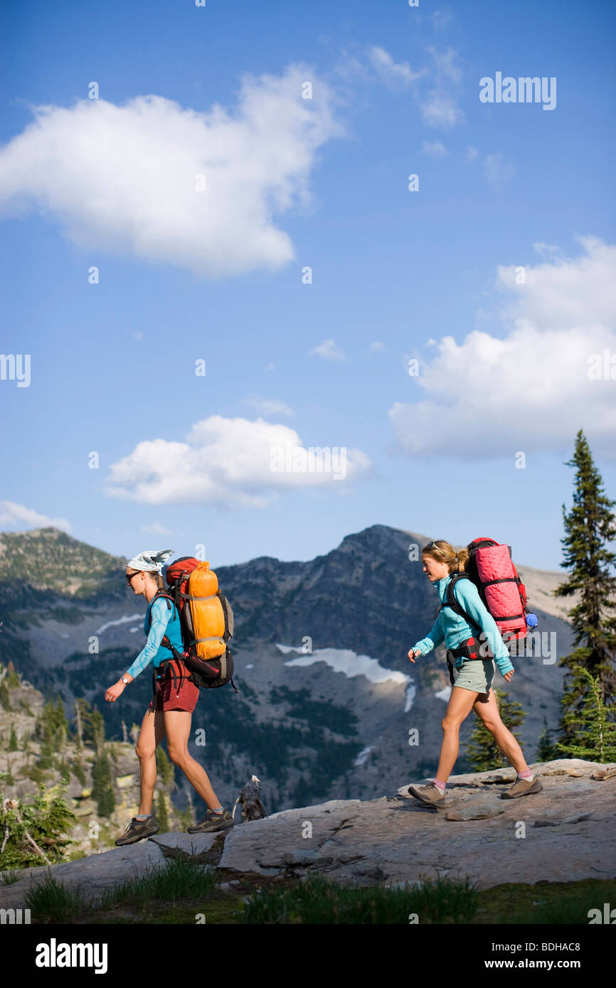 Two adult women backpacking in a wilderness area under a bright blue ...