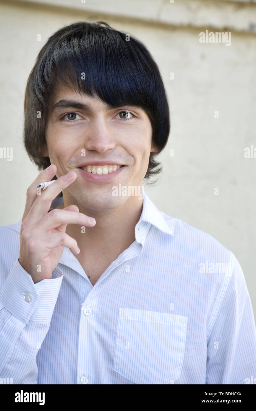 close up portrait of young smiling handsome smoking man to exhale smoke ...