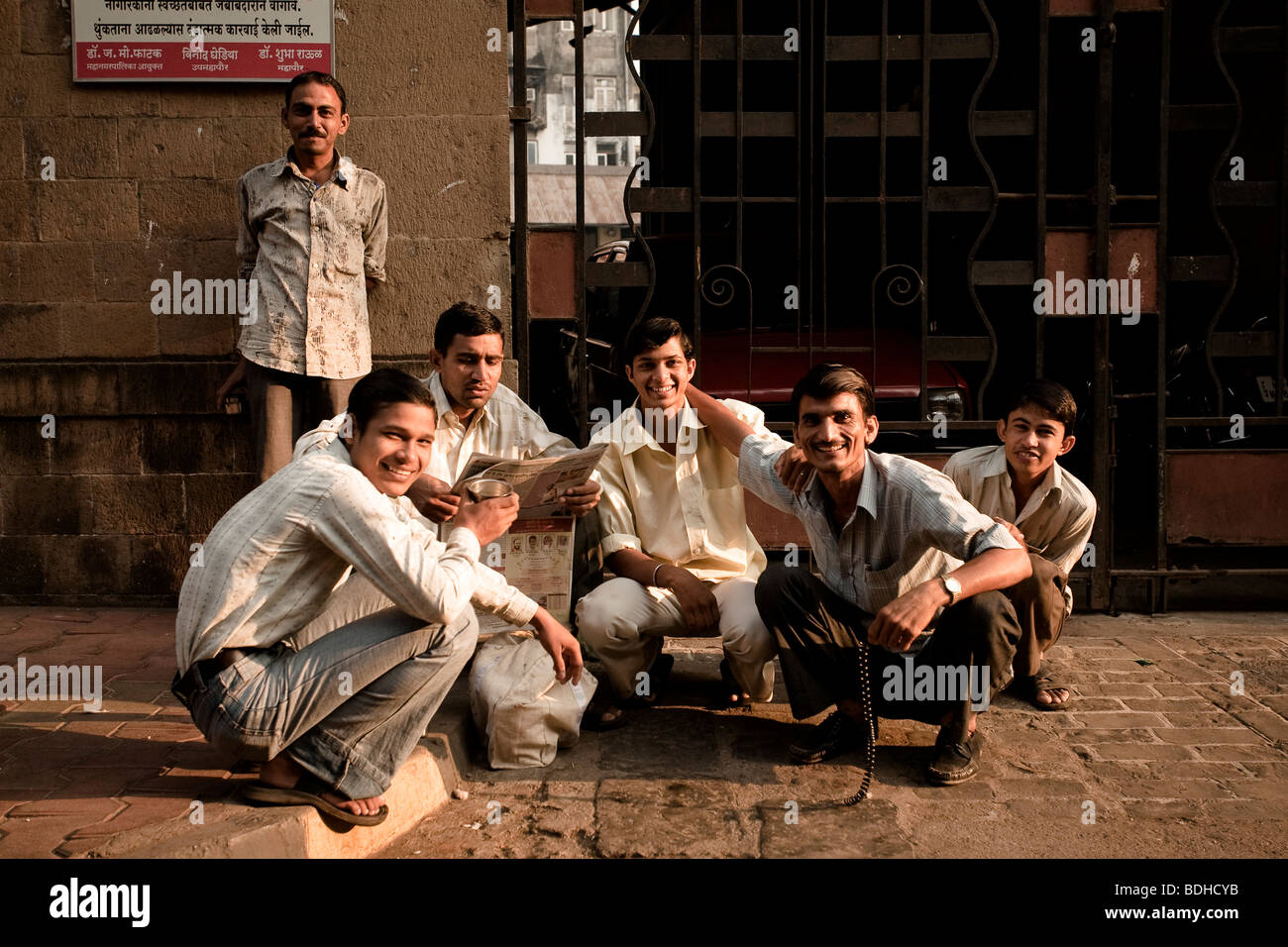 A group of young men hang out on a sidewalk during sunset Stock Photo ...