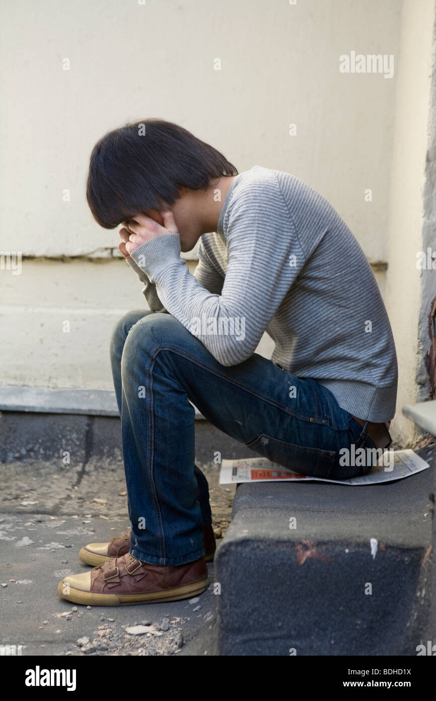 portrait of young serious handsome man sitting on on the doorstep ...