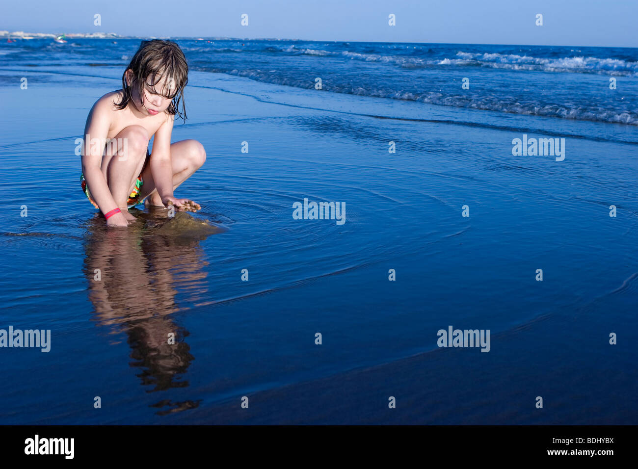 Little cute girl playing in sand on shore in sunset Stock Photo - Alamy