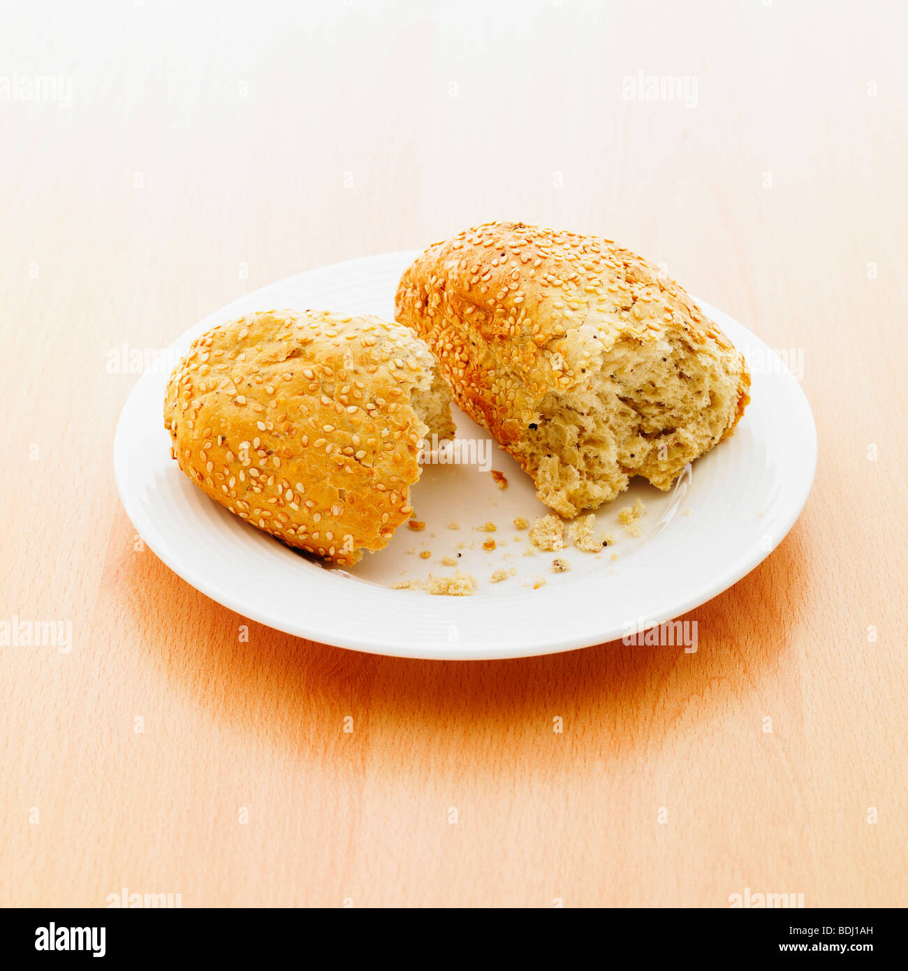 A broken sesame seed bread roll on a plate Stock Photo - Alamy