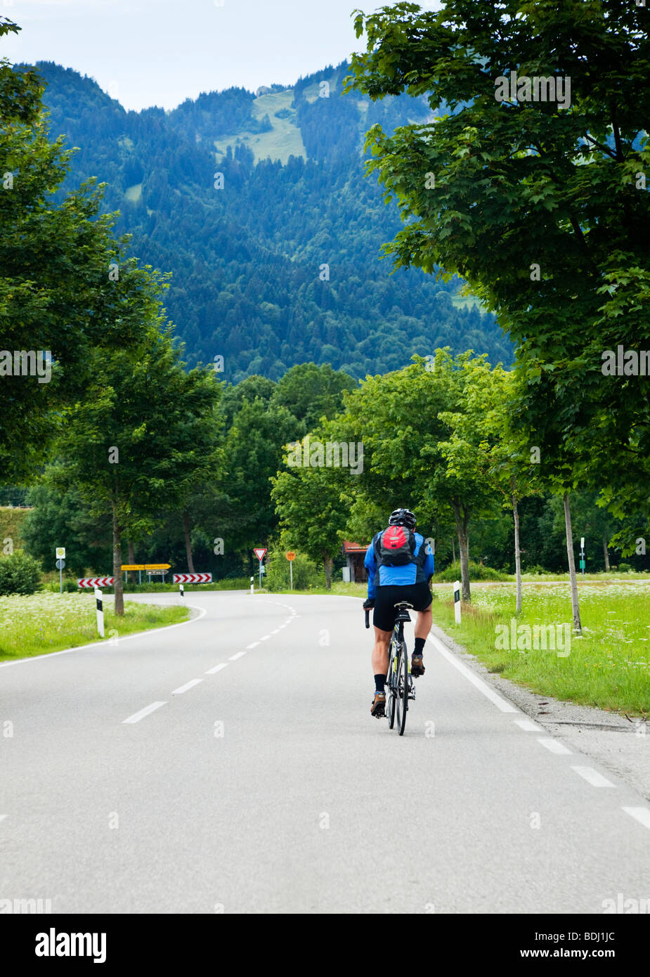 Cycling - Lone cyclist riding on a Bavarian forest road in southern ...