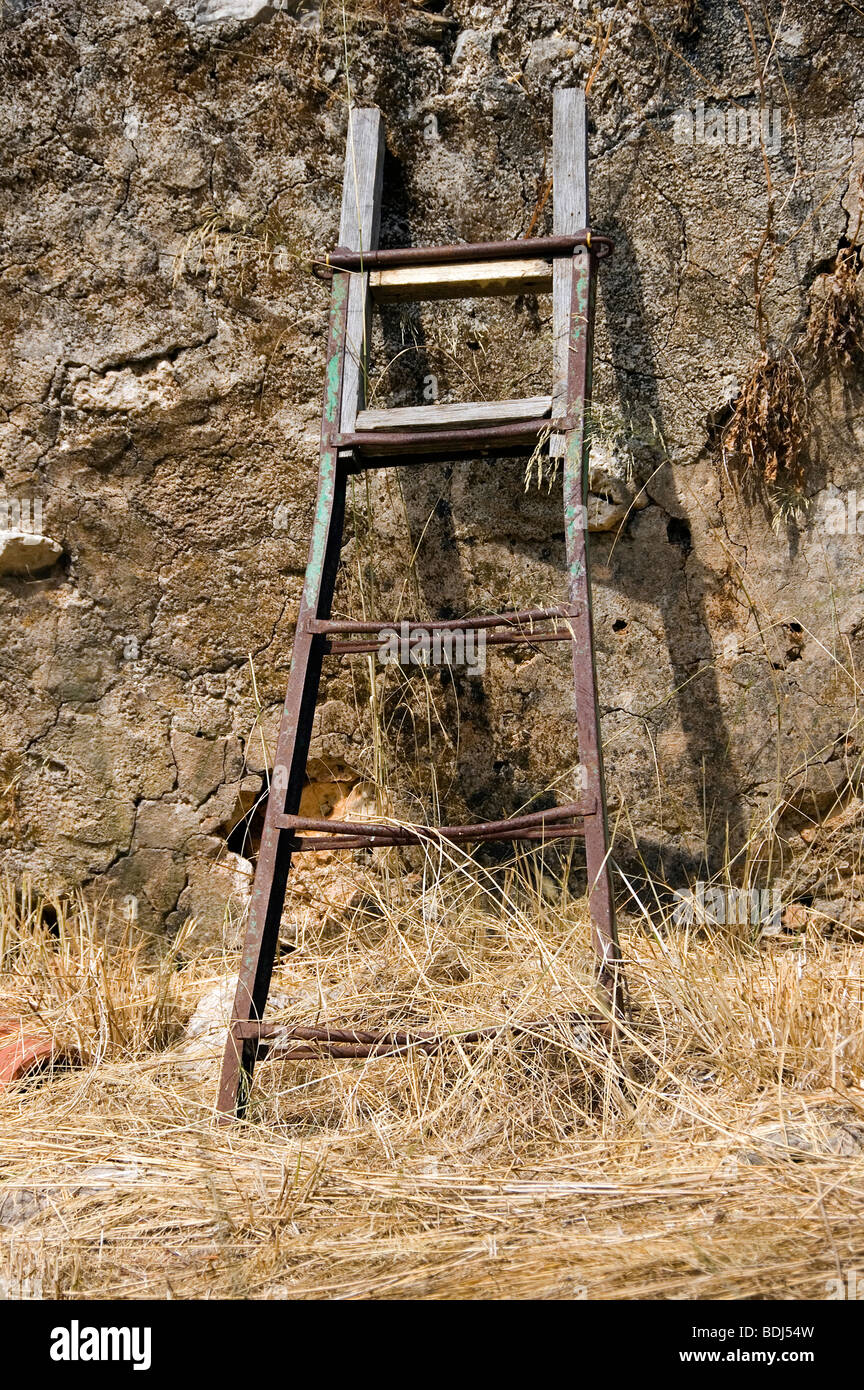 Rusty broken ladder against a weathered wall surface. Abstract ...