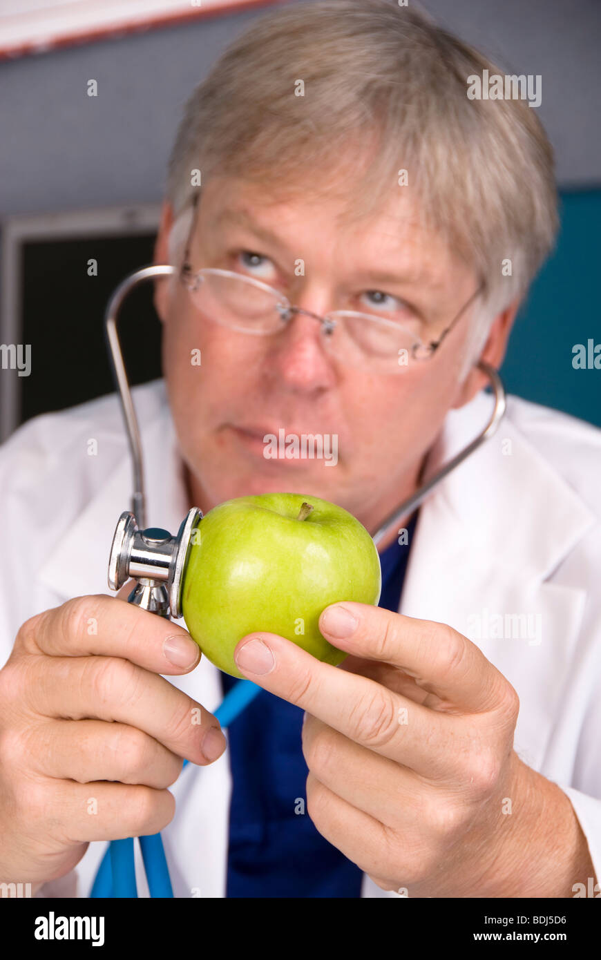 A doctor examines an apple with his stethoscope. Good image for healthy ...
