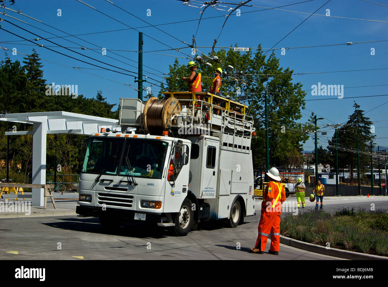 Electricians on truck roof deck installing new electric trolley cables ...