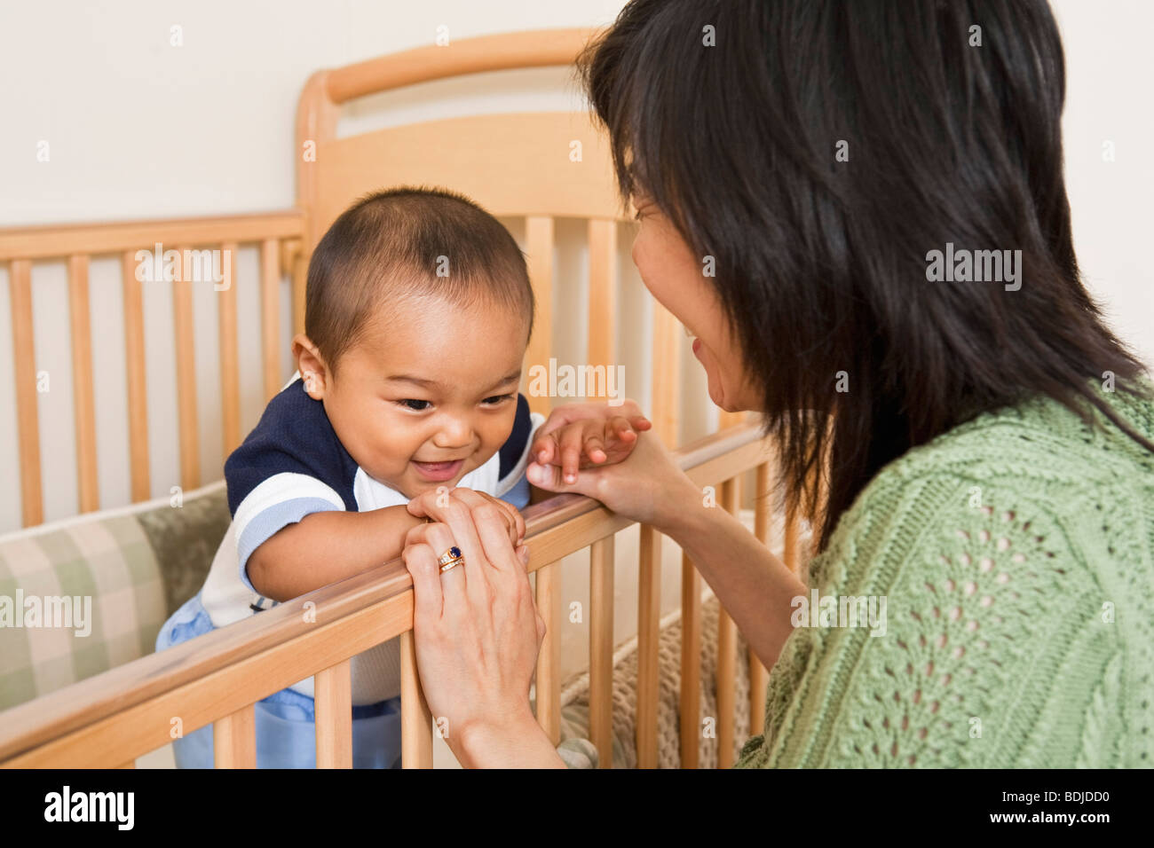 Baby inside Crib, Holding Hands with Mother Stock Photo - Alamy