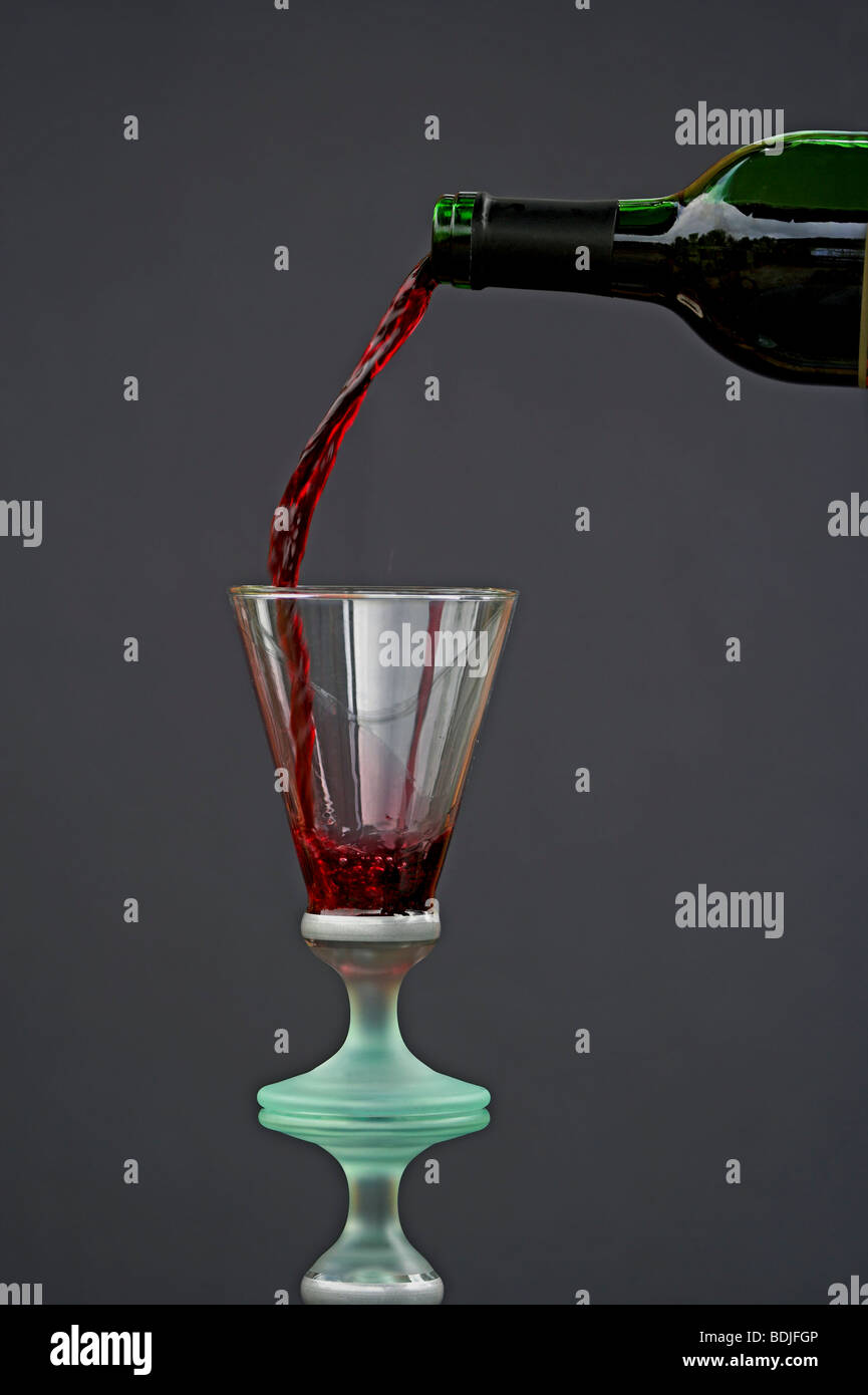 Red Wine being poured from a bottle into a glass with plain background ...