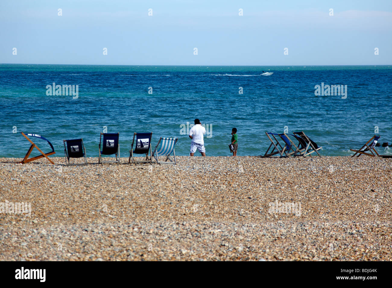 ENGLAND, East Sussex, Eastbourne, Man and boy on the beach with deck ...