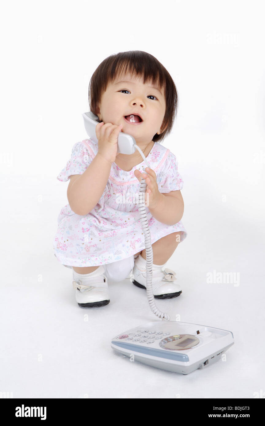 Baby girl crouching and holding telephone,Child Stock Photo - Alamy