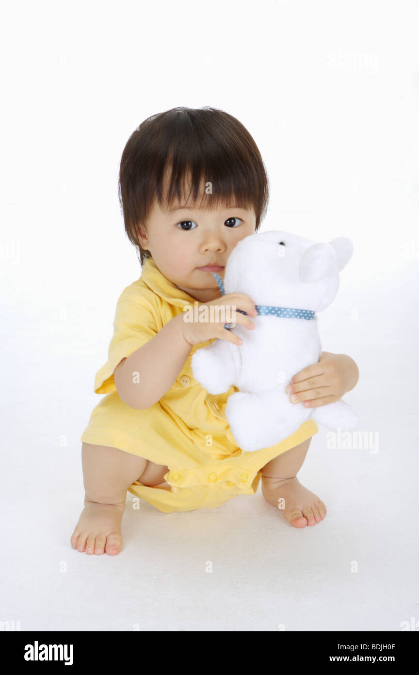 Baby girl crouching and holding a toy,Child Stock Photo - Alamy