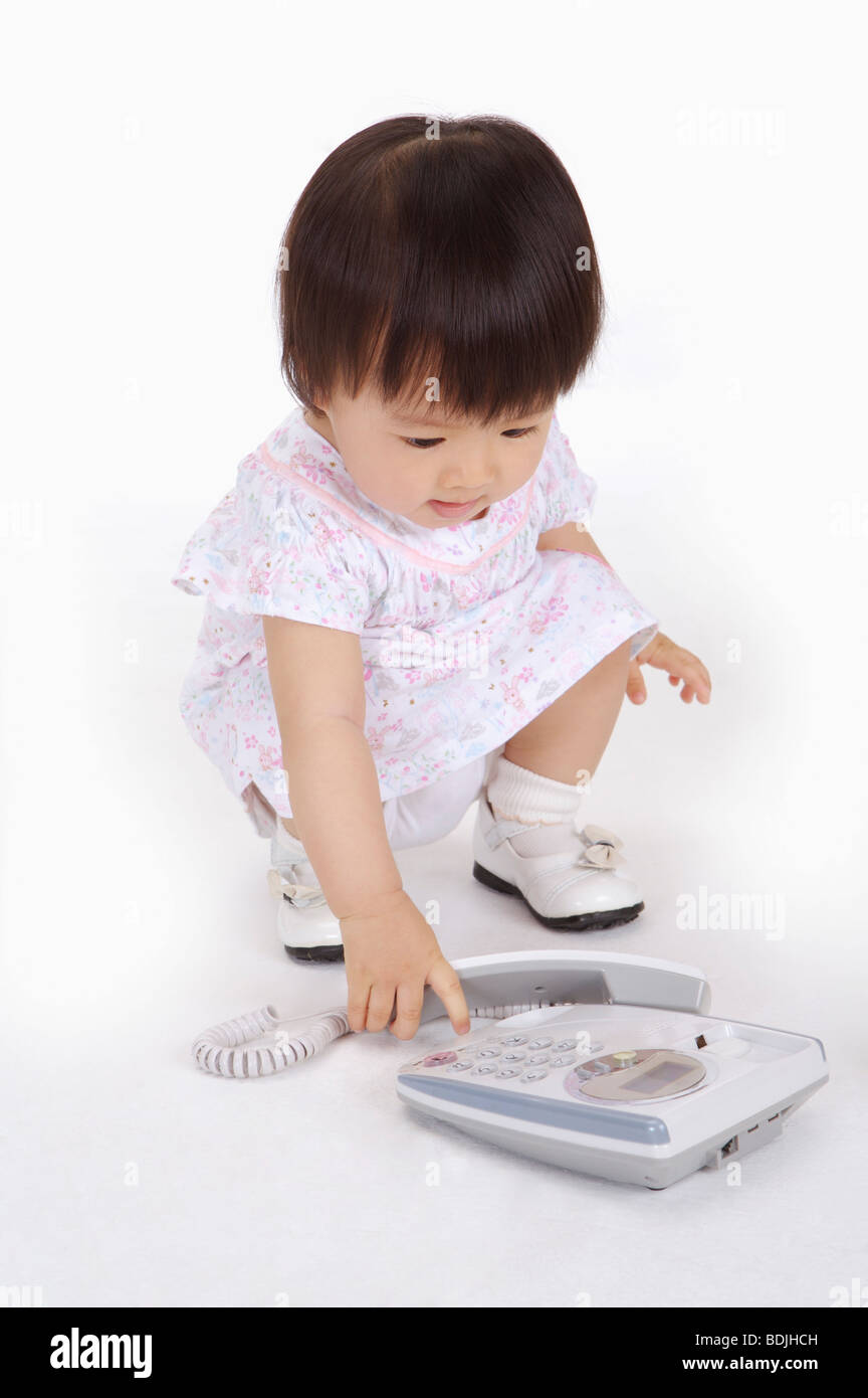 Baby girl crouching and pressing the telephone,Child Stock Photo - Alamy